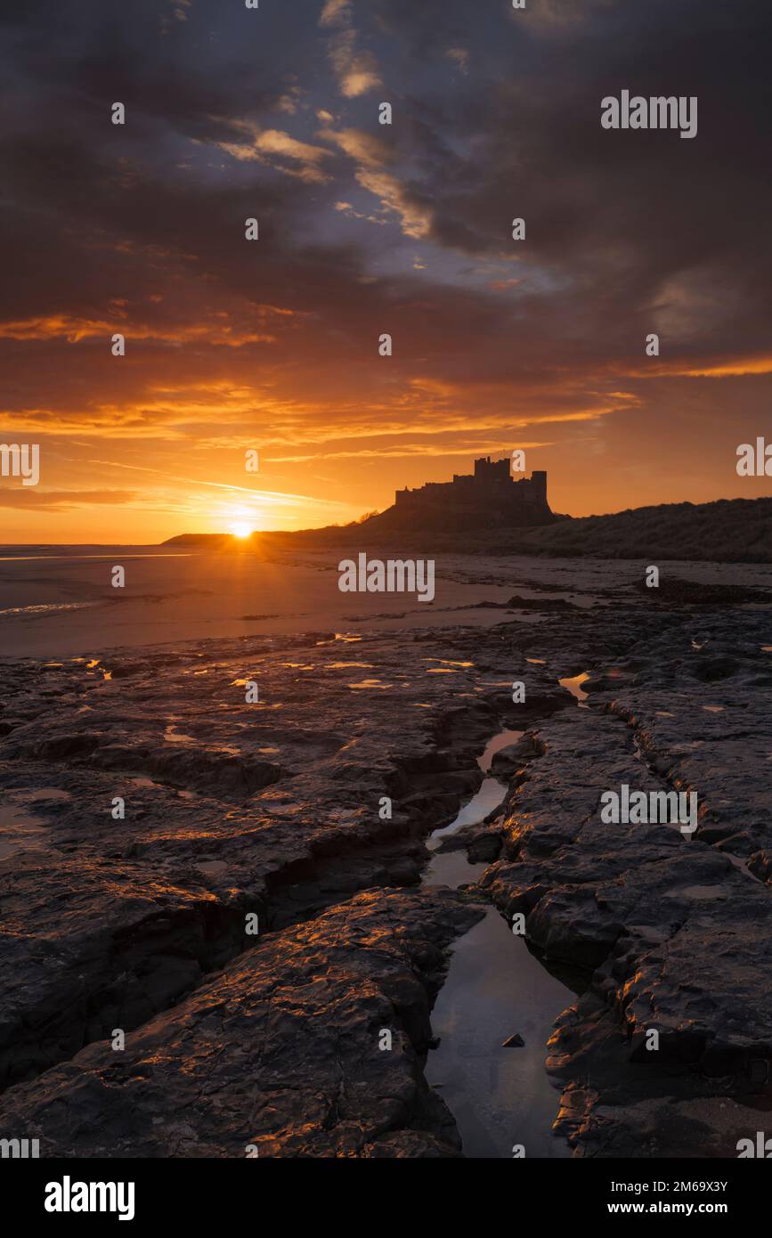 Bamburgh Castle at first light from a Whin Sill rock shelf north of the ...