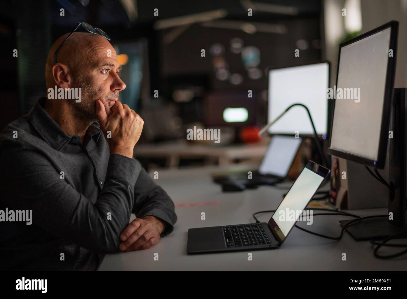 Shot of thinking businessman using laptop and computer while sitting at ...