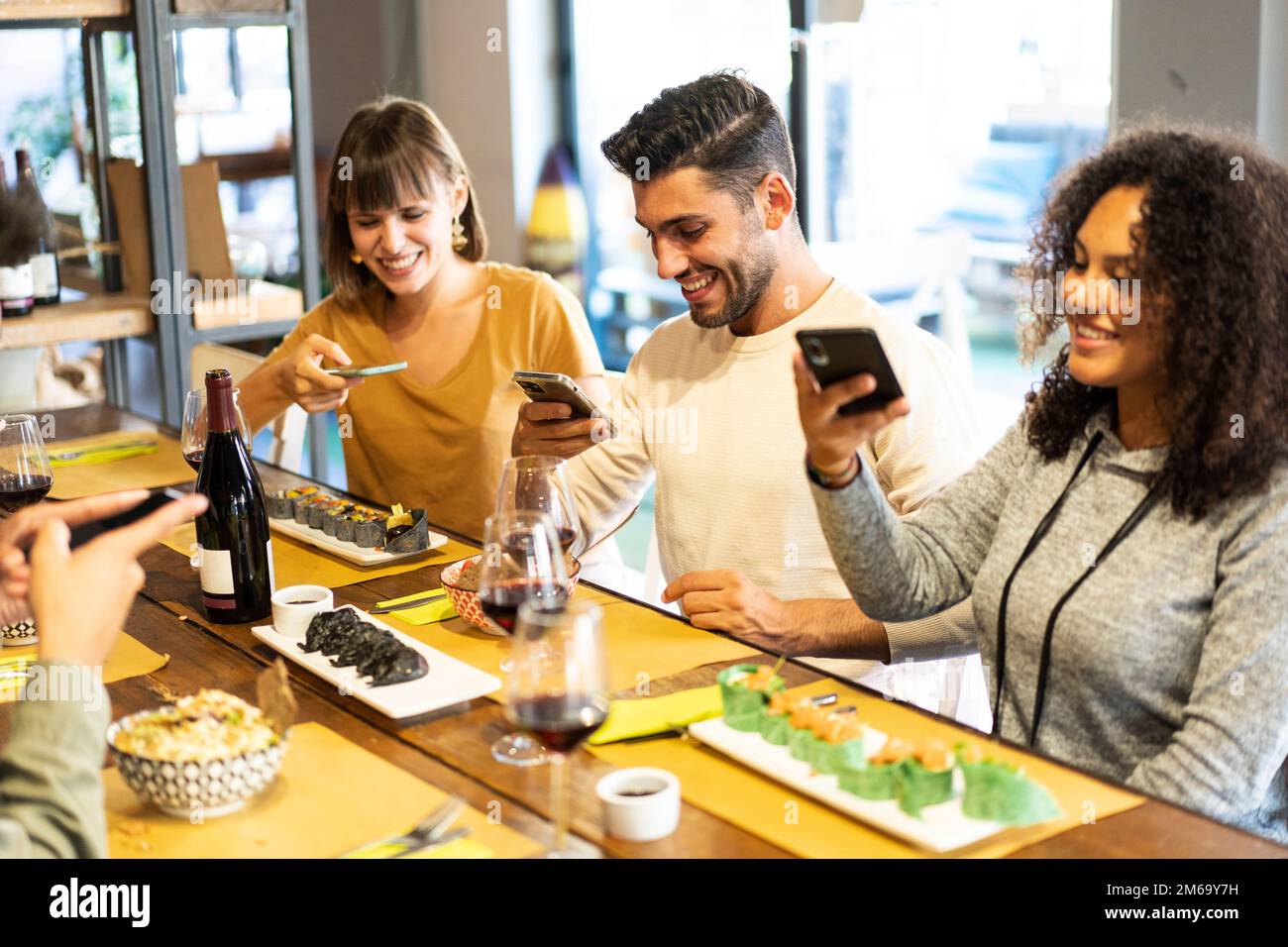 Multicultural trendy friends photographing fusion food with smartphone ...