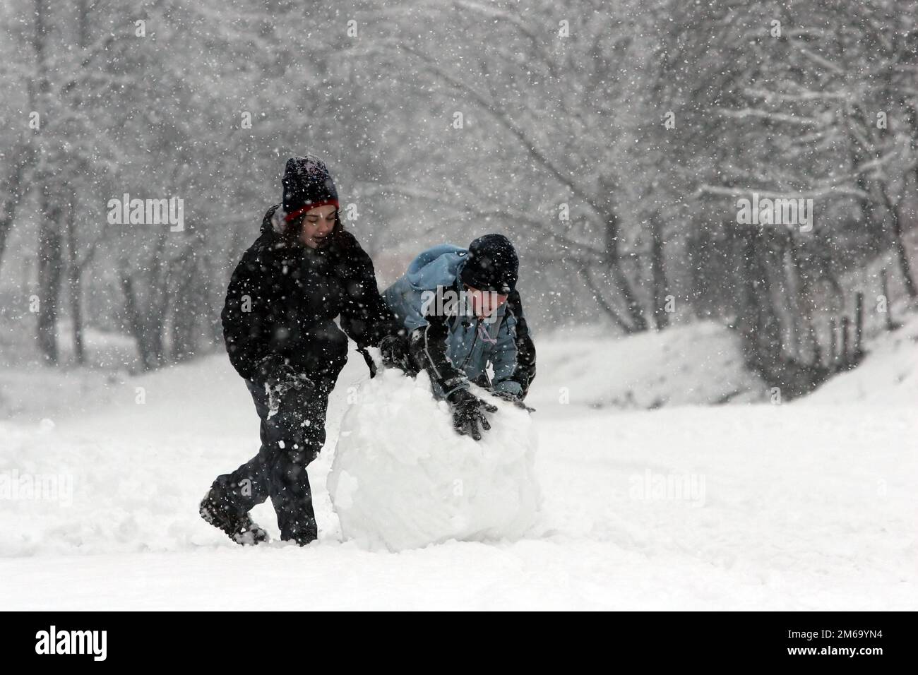 Children rolling snowball snowman hi-res stock photography and images ...