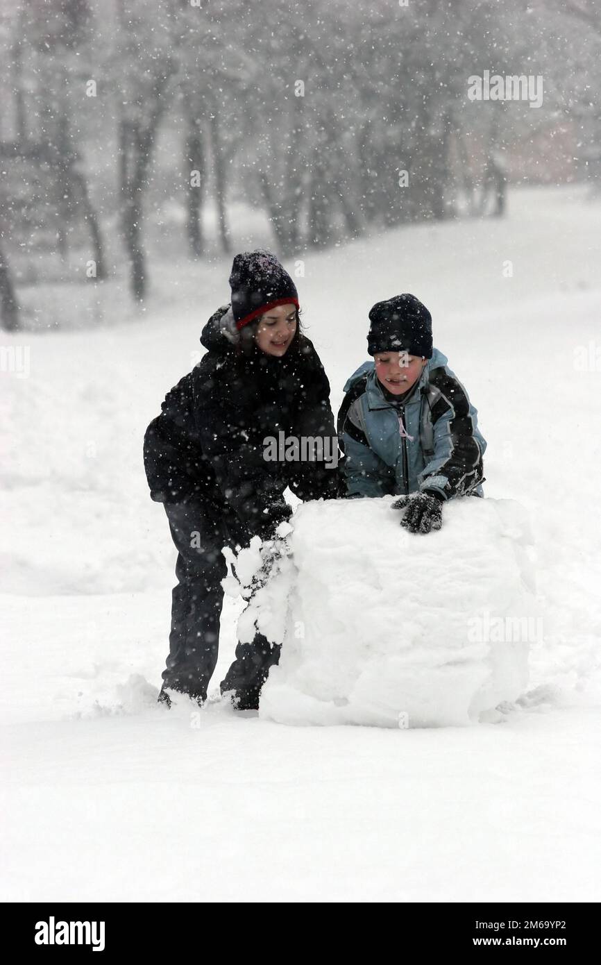 Children rolling snowball snowman hi-res stock photography and images ...