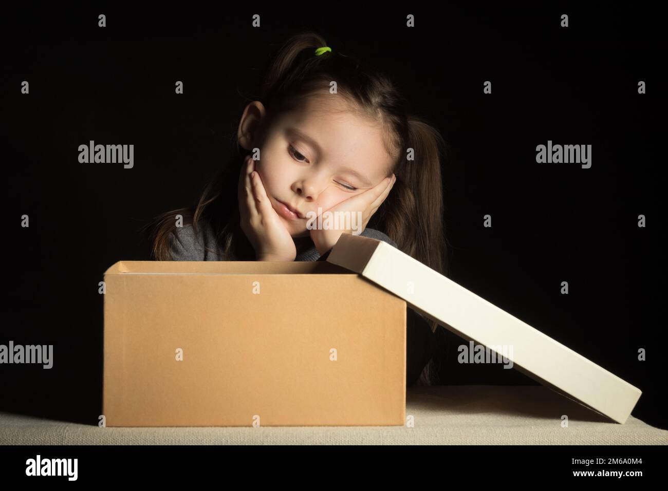 Upset and disappointed little girl opens a long-awaited parcel with a ...