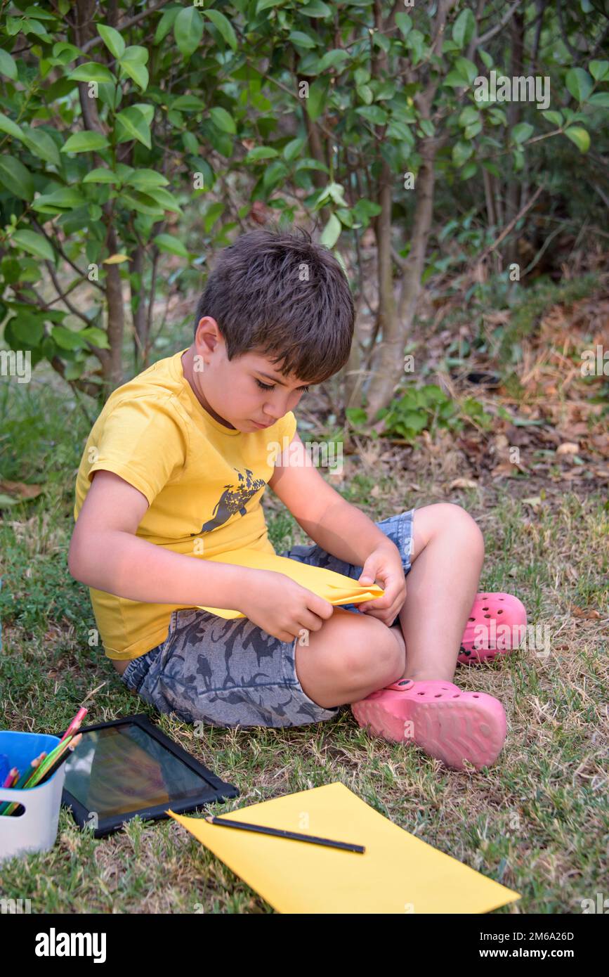 Boy sitting and relaxing on a hill reading a book in a meadow concept ...