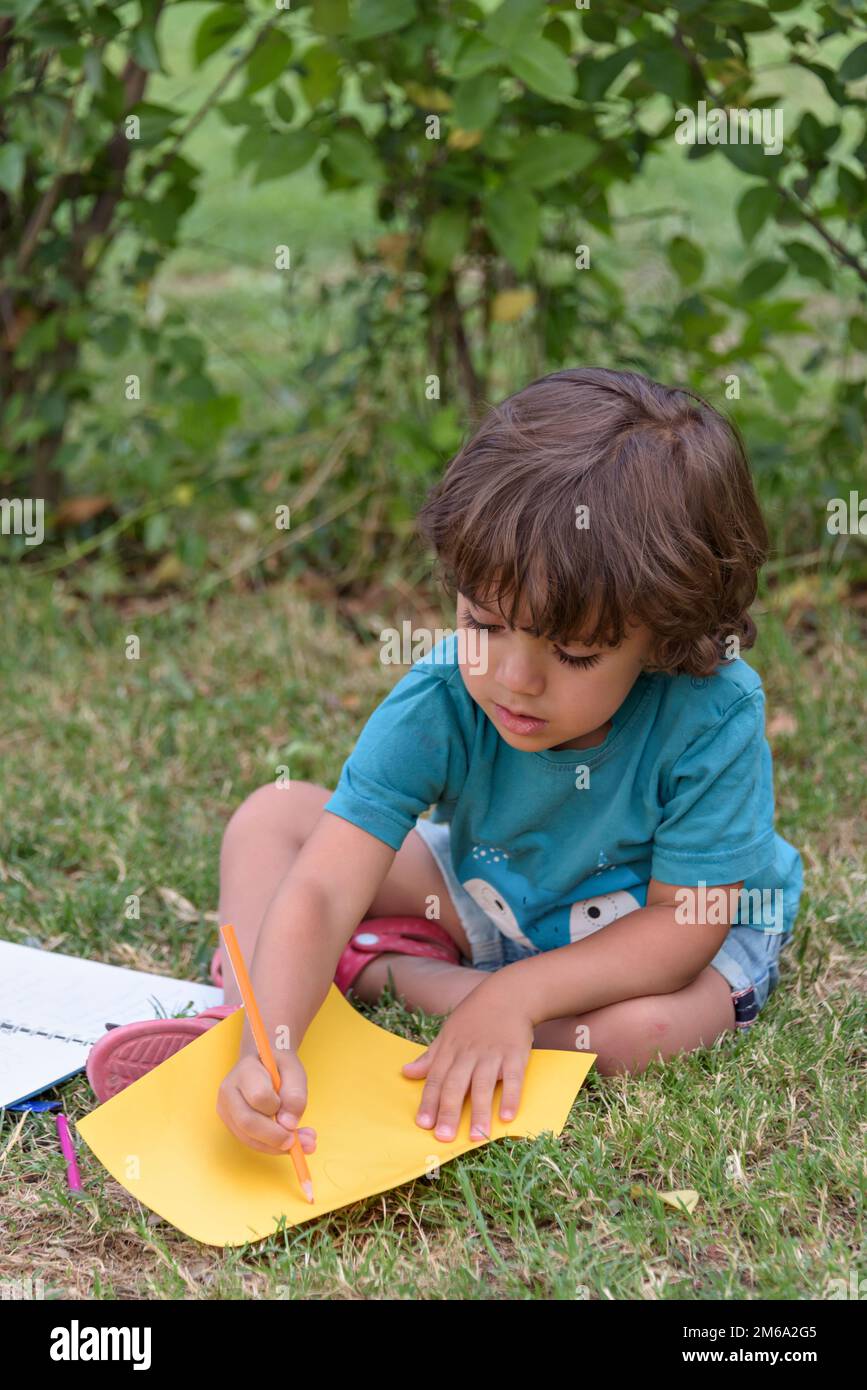 Primary school child lying on the grass doing homework Stock Photo - Alamy