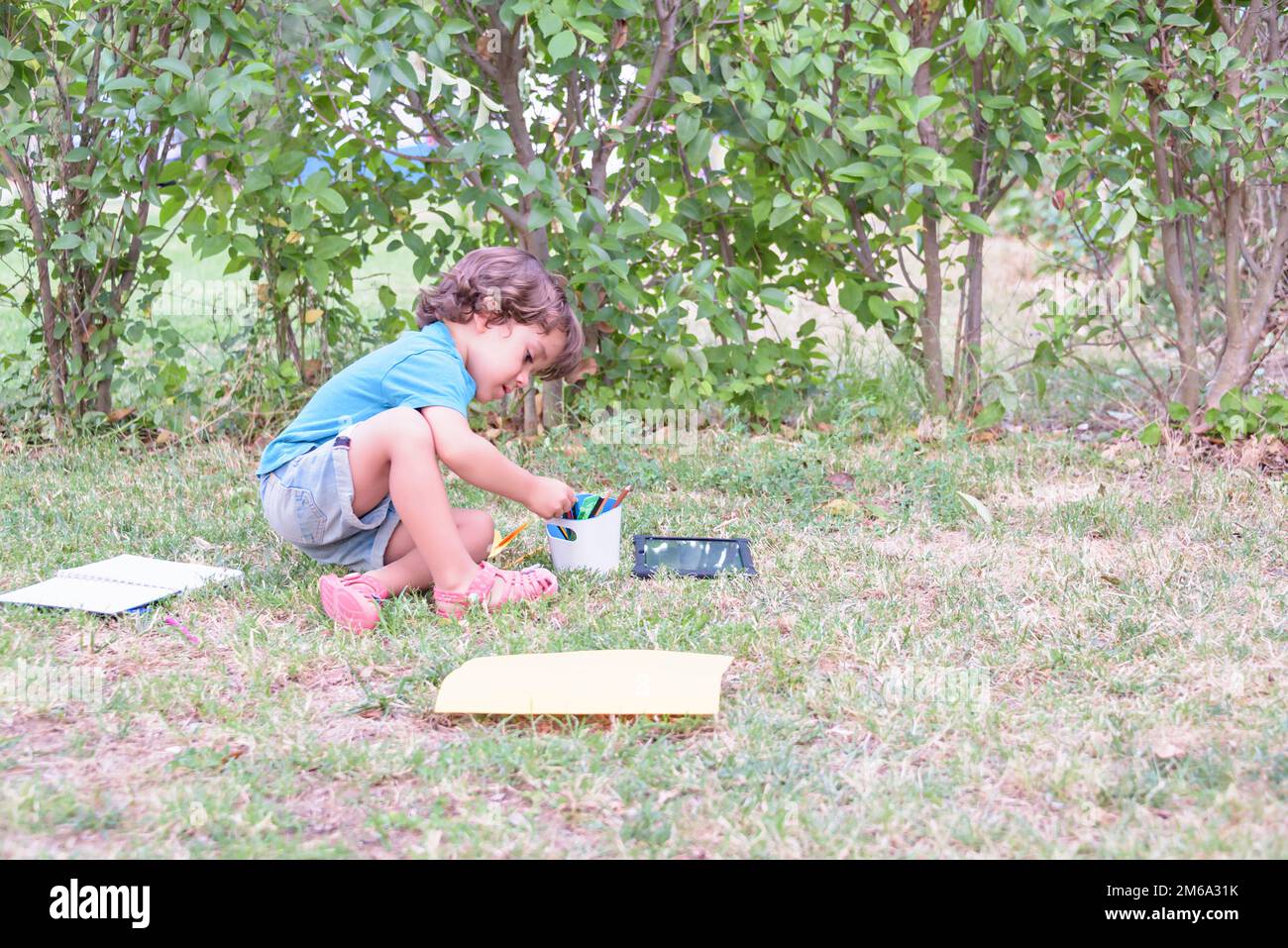 Primary school child lying on the grass doing homework Stock Photo - Alamy