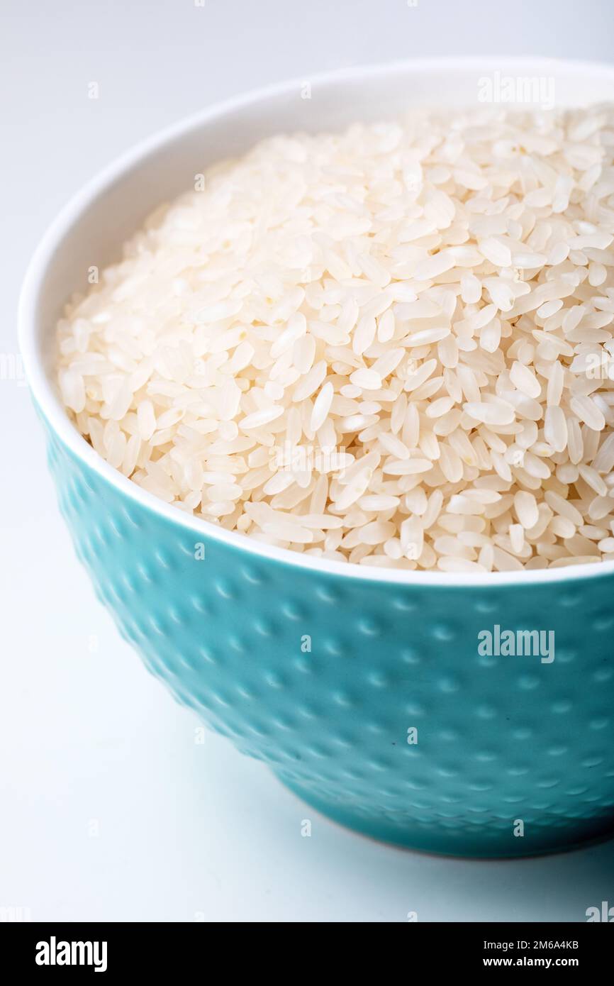 Bowl of raw organic rice on white background. Blue bowl full of rice on ...
