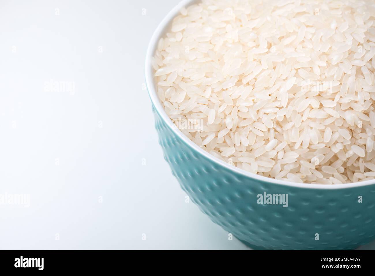 Bowl of raw organic rice on white background. Blue bowl full of rice on ...