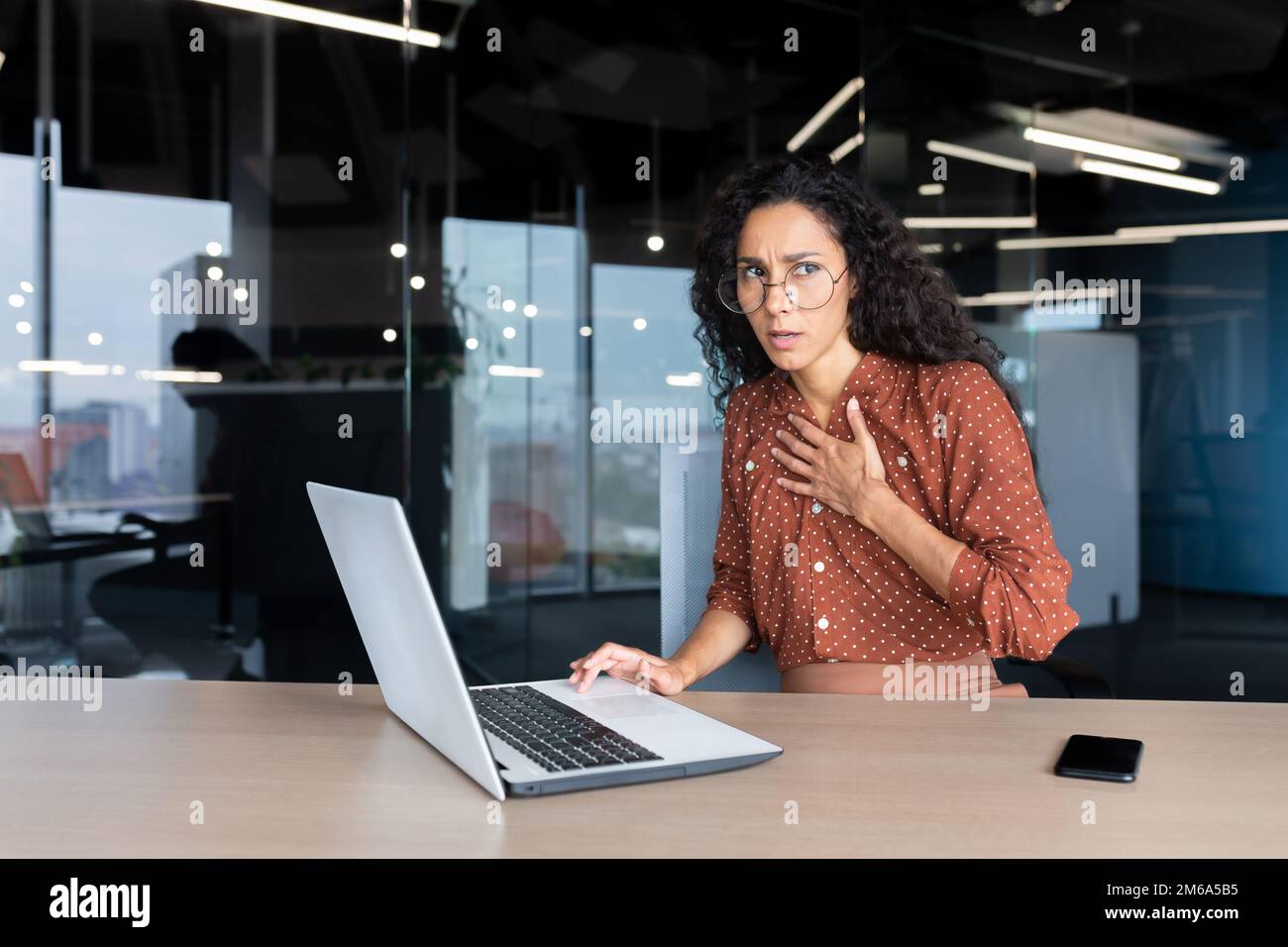 Anxious and scared business woman working inside office, Hispanic woman ...