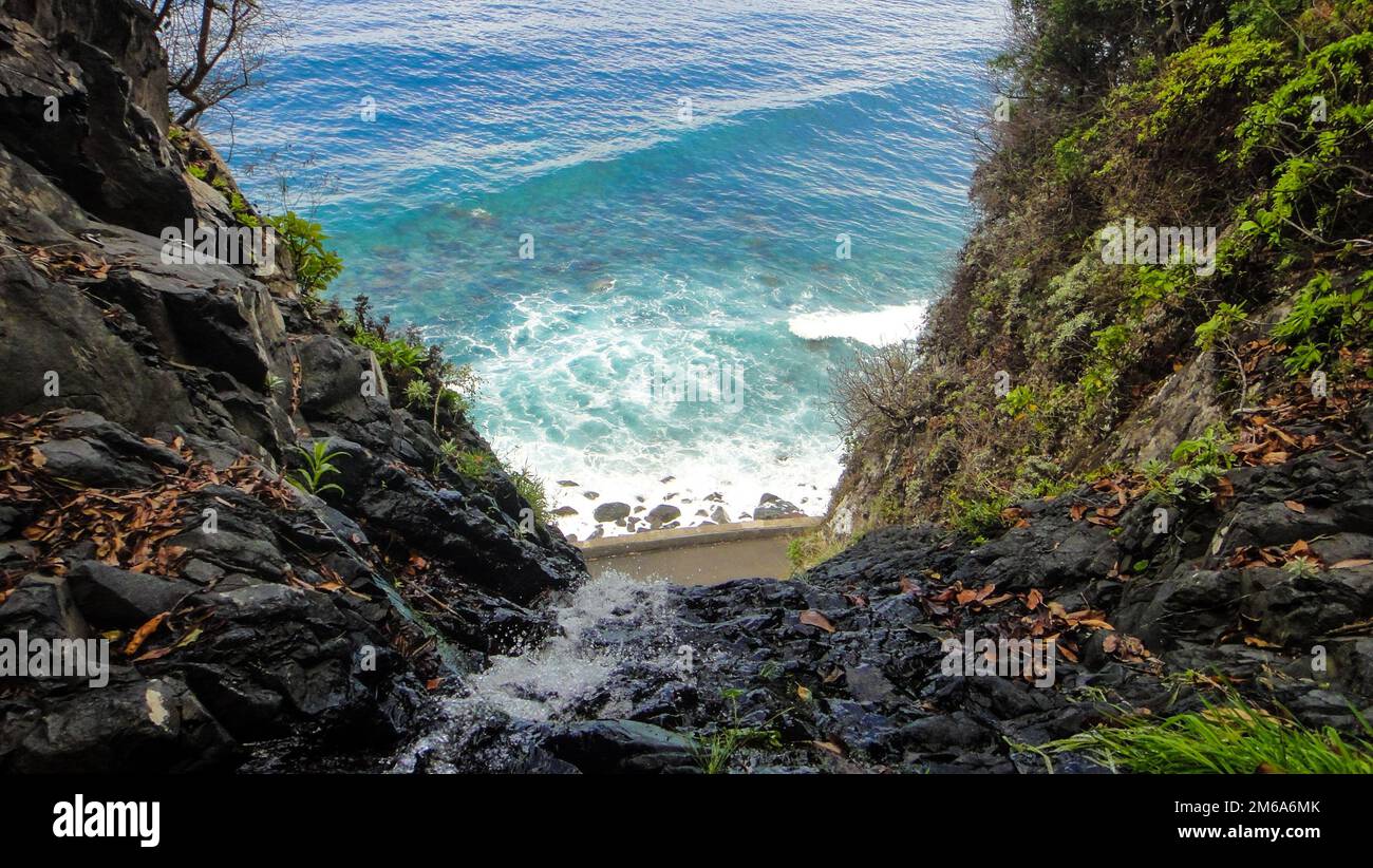 A high-angle shot of a stream falling down a rocky seashore Stock Photo ...