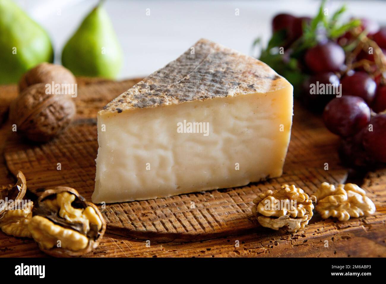 Organic cheese on a wood table with grapes and walnuts Stock Photo - Alamy