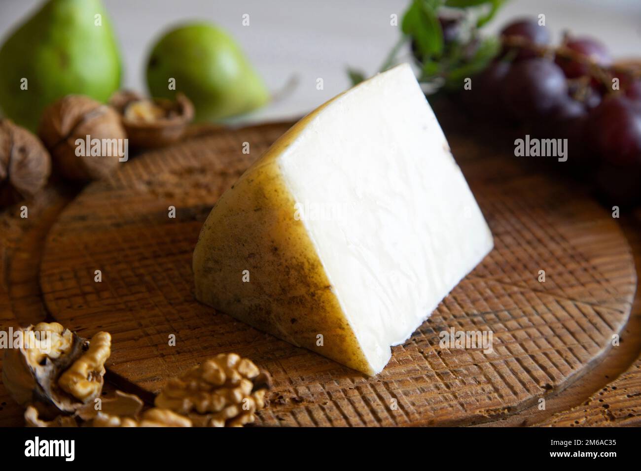 Organic cheese on a wood table with grapes and walnuts Stock Photo - Alamy