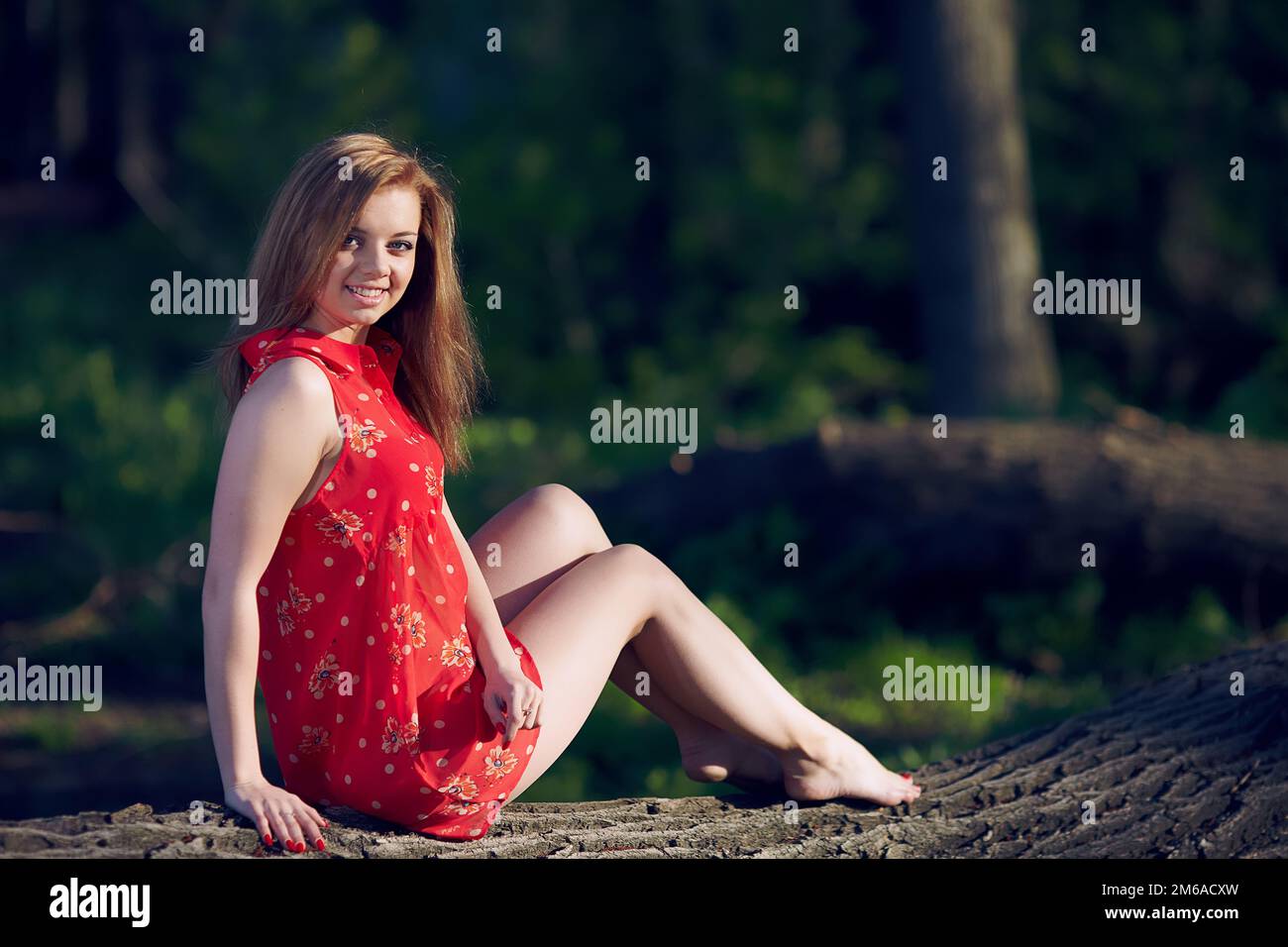Girl siting on a log Stock Photo - Alamy