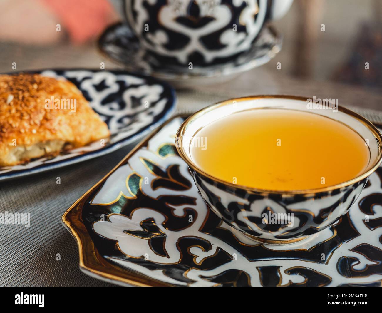Fresh, hot bun and a cup of fragrant tea. Sunny, clear day. Close-up ...