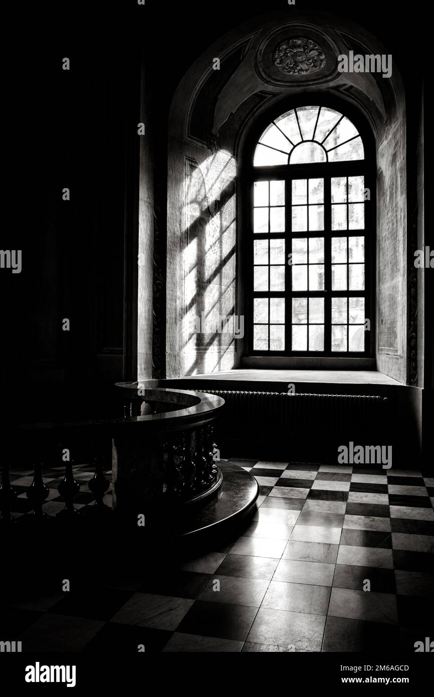 A grayscale shot of an interior of a vintage house with an open window ...