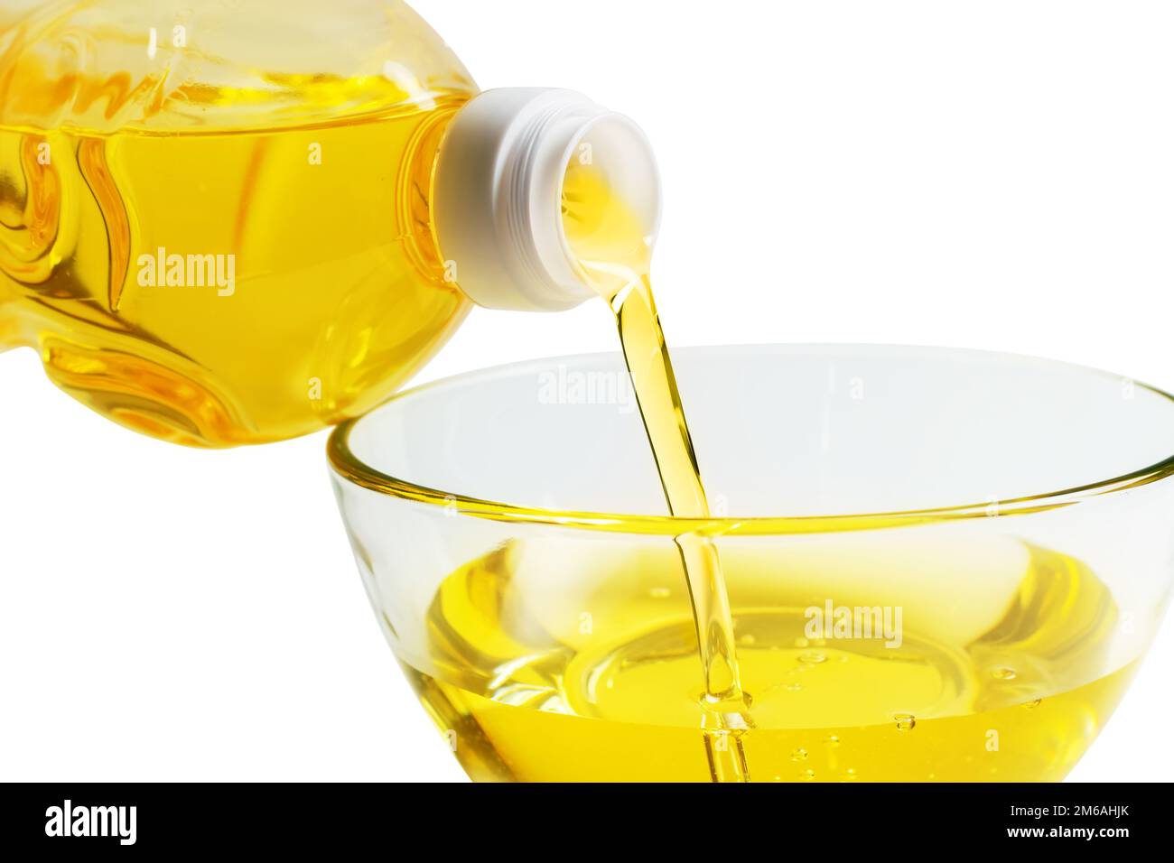 Sunflower oil pouring from bottle in a glass bowl. Isolated on white ...