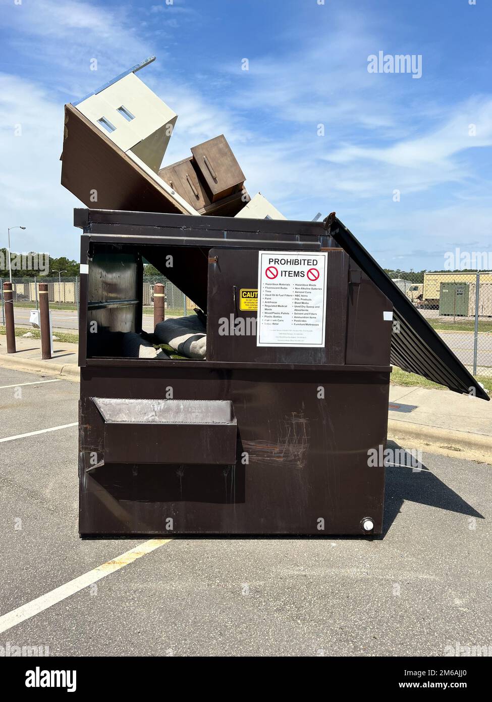A dumpster sits full of furniture in an empty parking lot of Fort Bragg ...