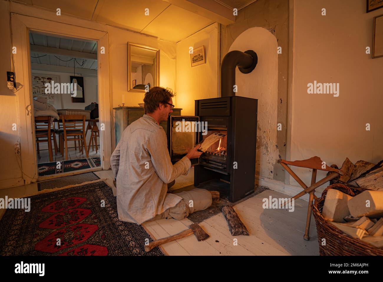 Man Adding Logs To A Wood Burning Stove Fire Stock Photo - Alamy