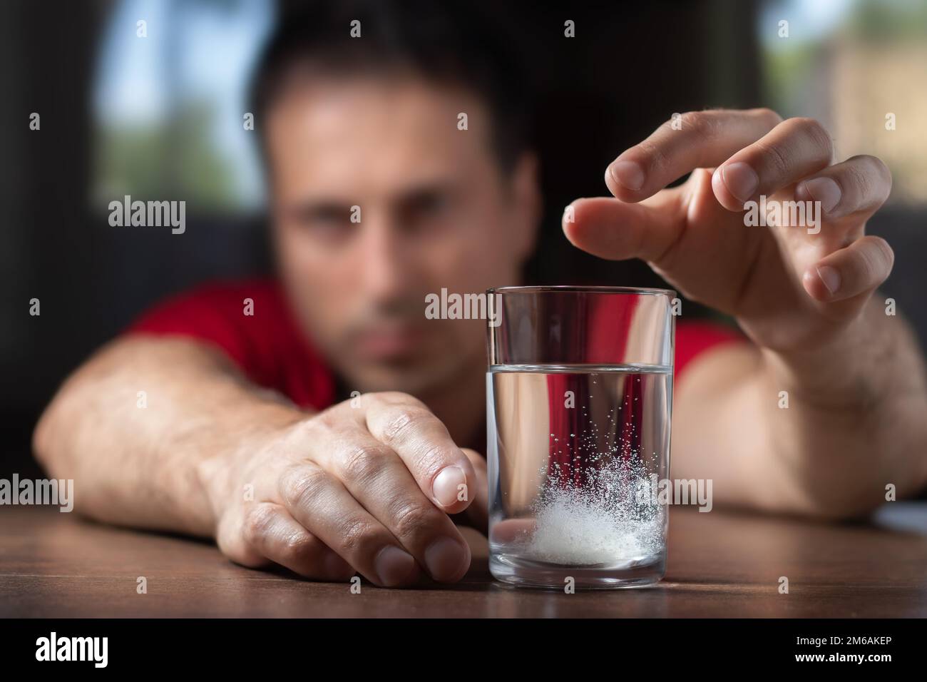Man throwing a hangover pill into a glass of water. Effervescent tablet ...