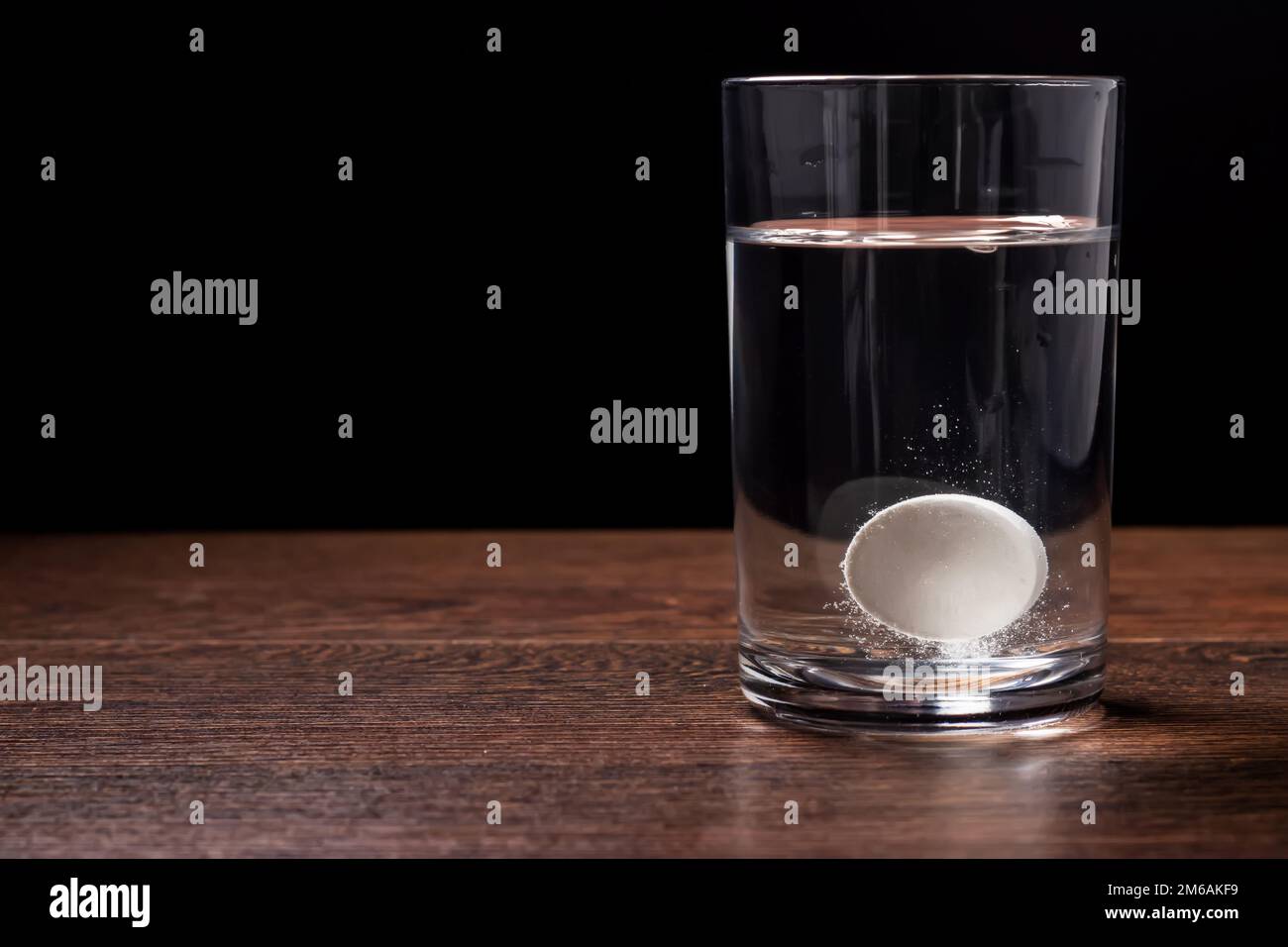 Effervescent tablet in a glass of water close-up on a black background ...