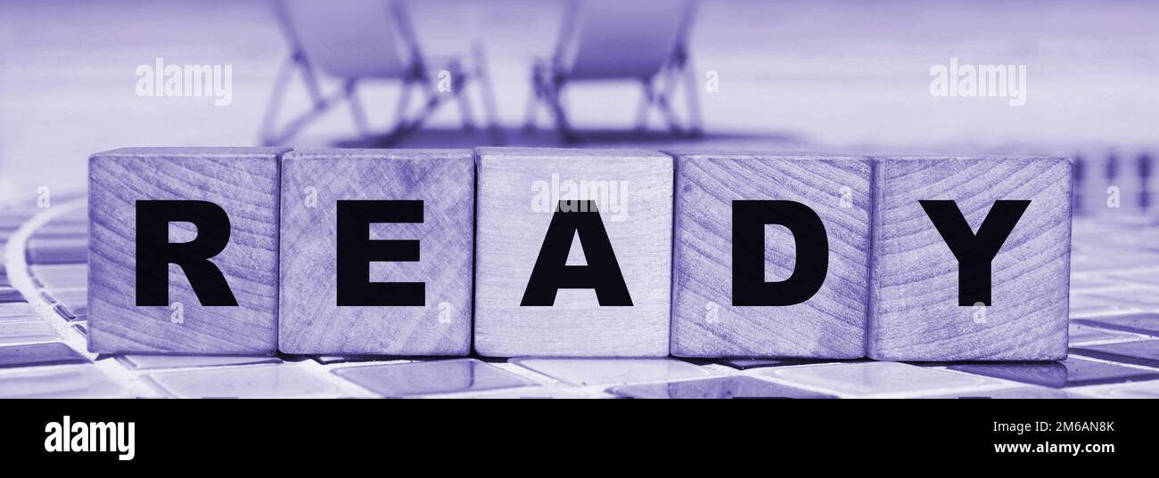 word ready made with wooden blocks standing on swimming pool border ...