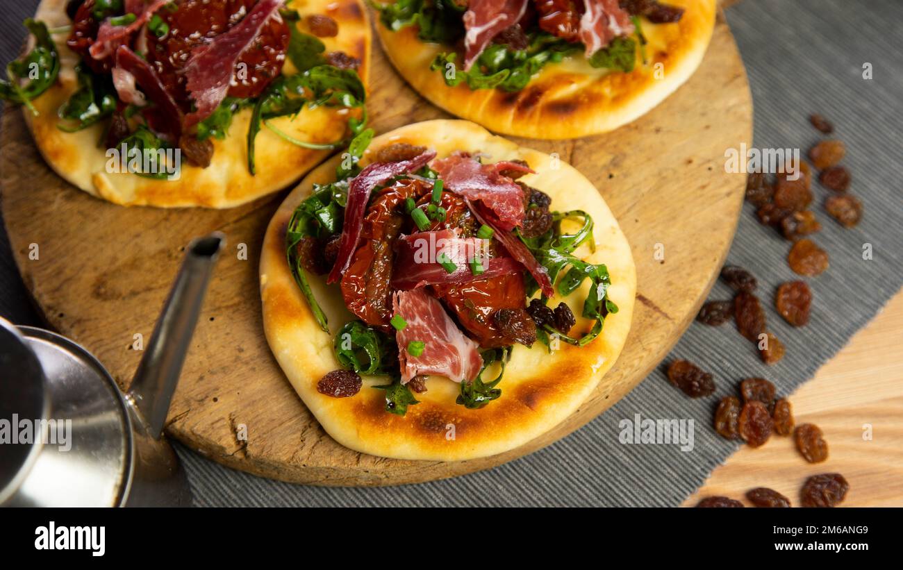 Mini pizza with Spanish Iberico ham, arugula and cheese Stock Photo - Alamy
