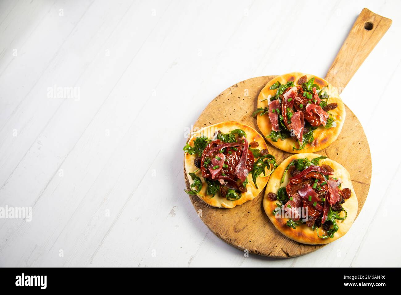 Mini pizza with Spanish Iberico ham, arugula and cheese Stock Photo - Alamy