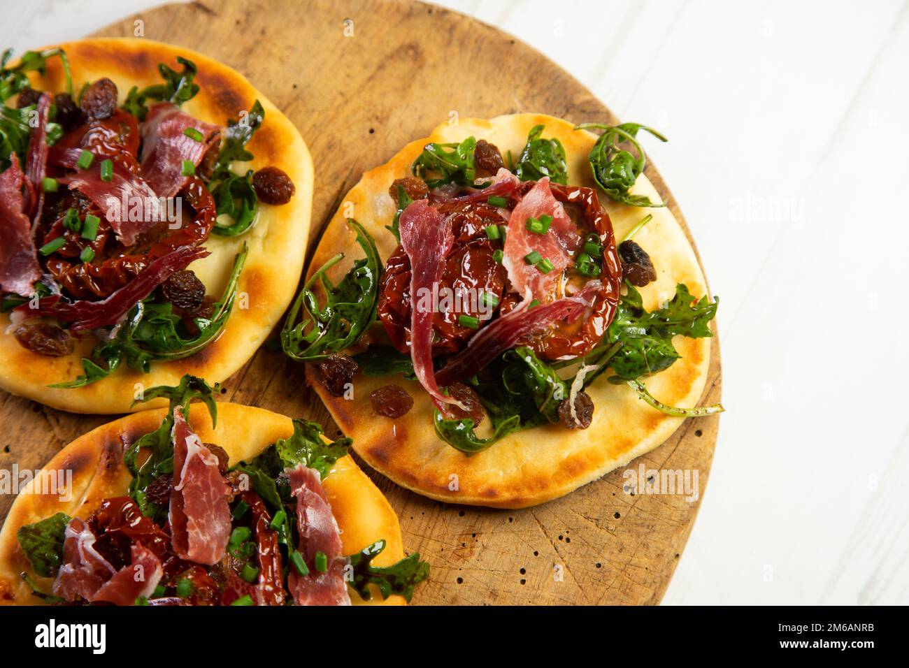 Mini pizza with Spanish Iberico ham, arugula and cheese Stock Photo - Alamy