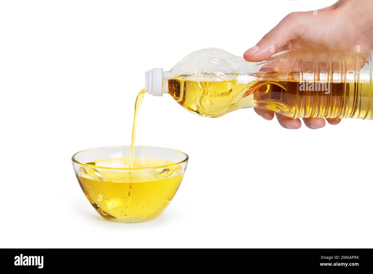 Sunflower oil pouring from bottle in a glass bowl. Isolated on white ...