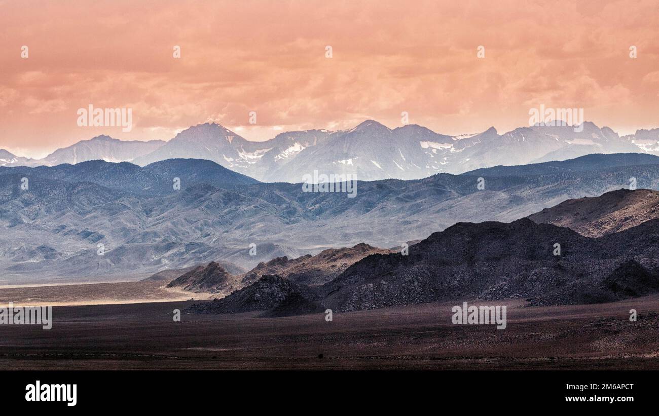 Backlit blue mountain ranges, one behind the other, staggered, evening ...