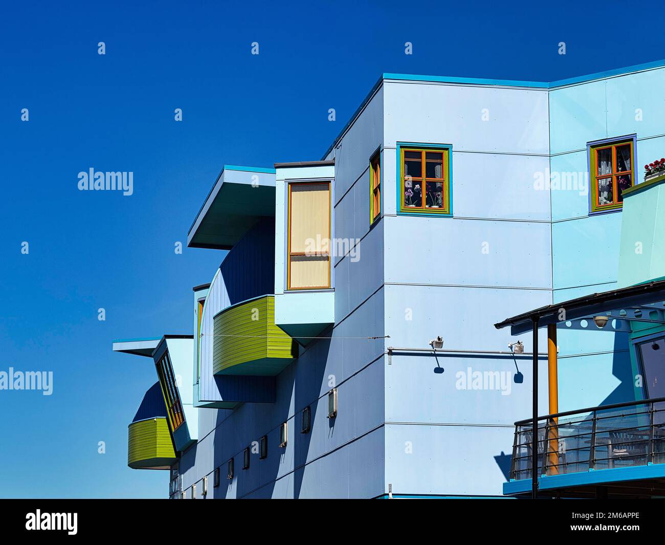 Light blue facade with colourful windows and balconies, residential ...