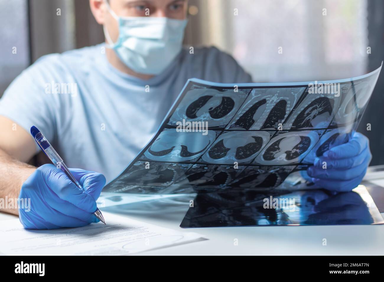 Doctor attentively examines the MRI scan of the patient and writes data ...