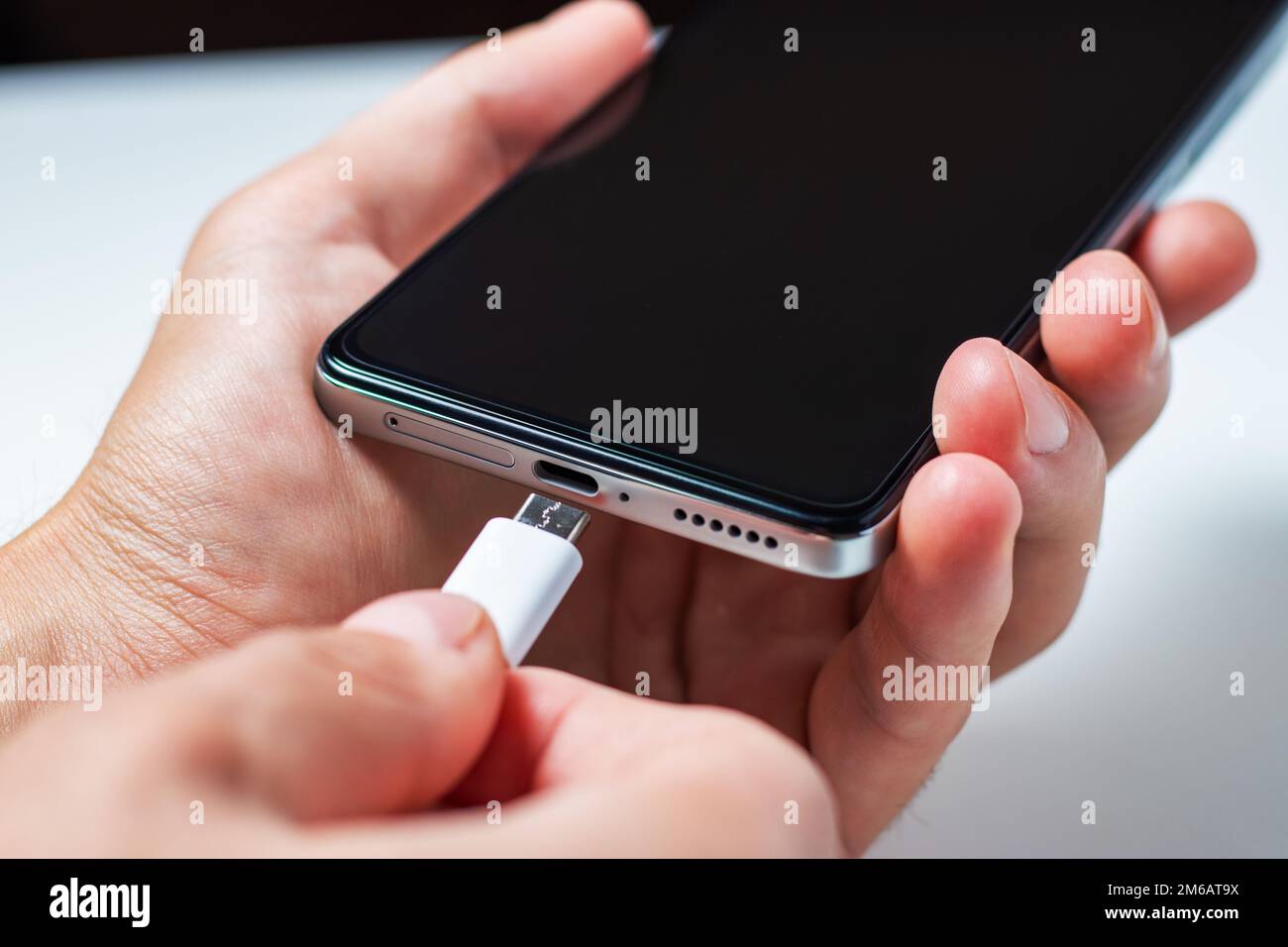 Charging a smartphone via a USB cable and a power supply. A black ...