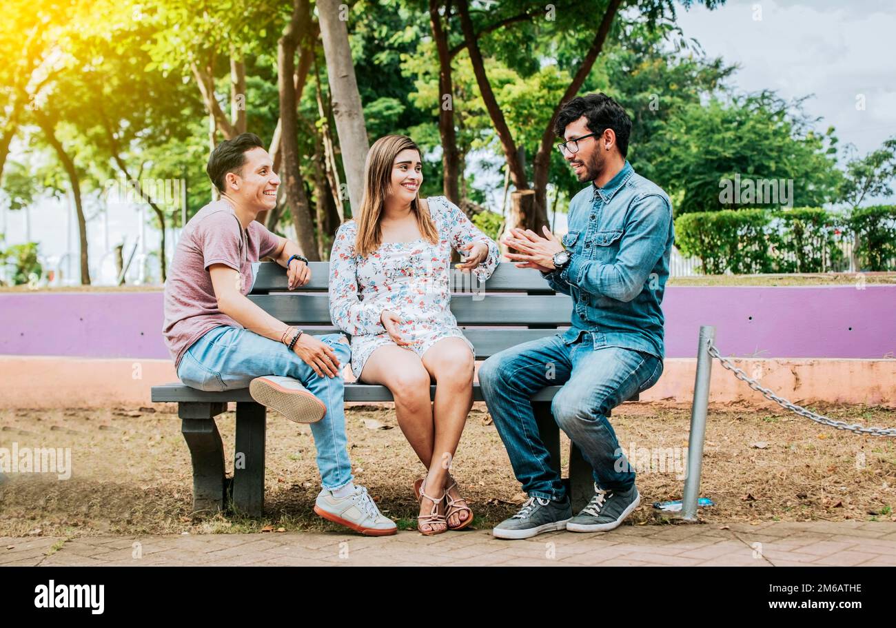 Three happy friends talking in a park. Three teenage friends talking ...