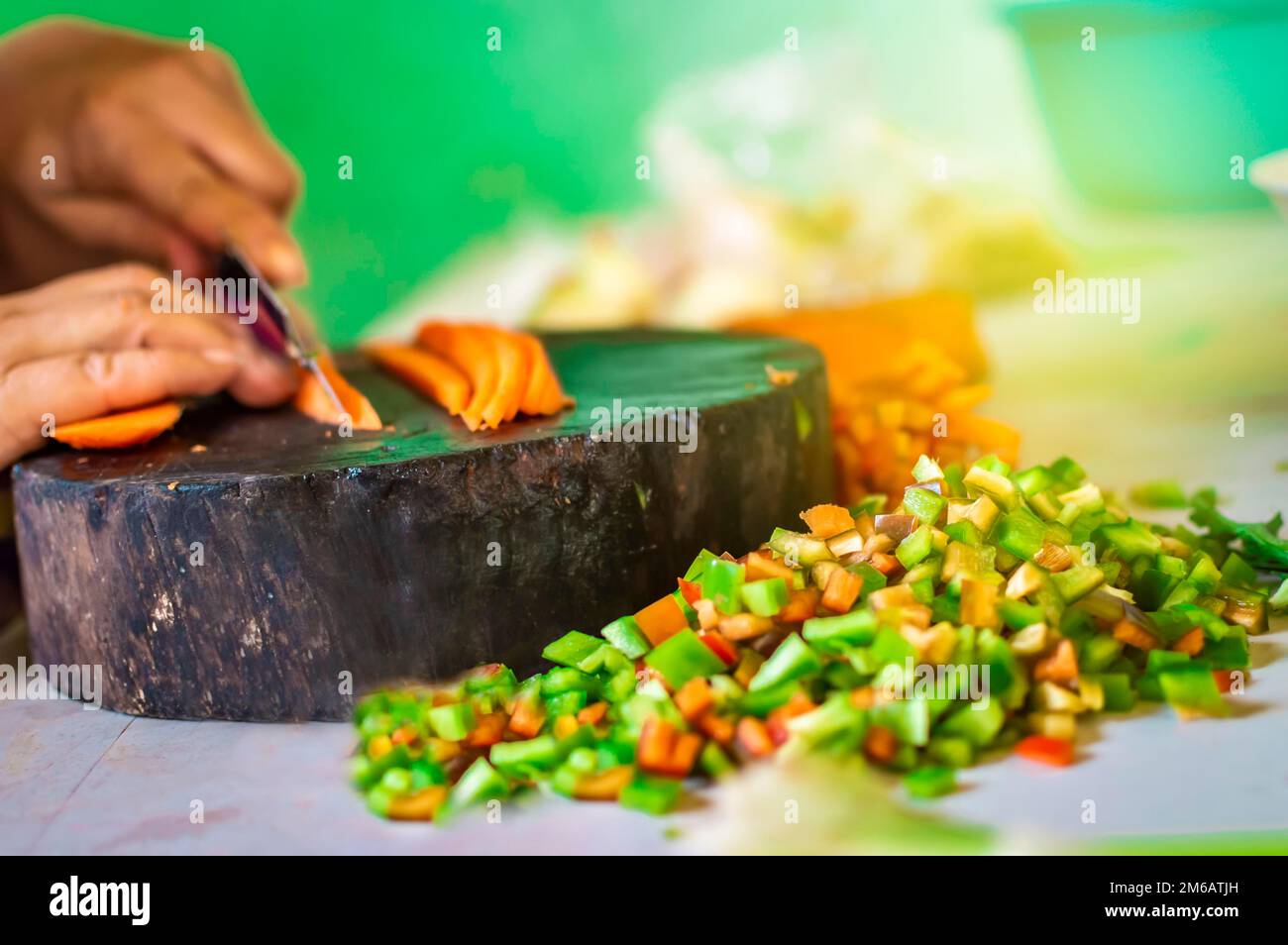 Hands cutting carrot pieces on a homemade chopper. Close up of hands ...