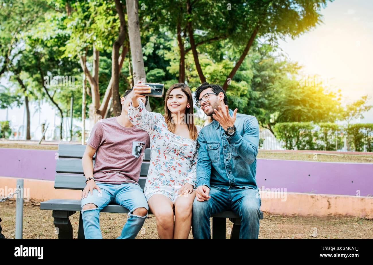 Three friends sitting on a bench taking a selfie, Three teenage friends ...