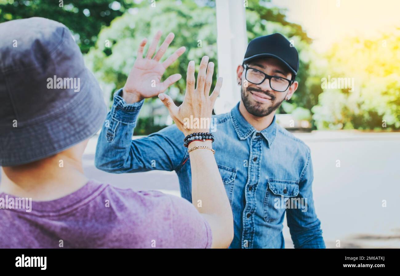 Back view of two smiling friends shaking hands on the street. Two ...