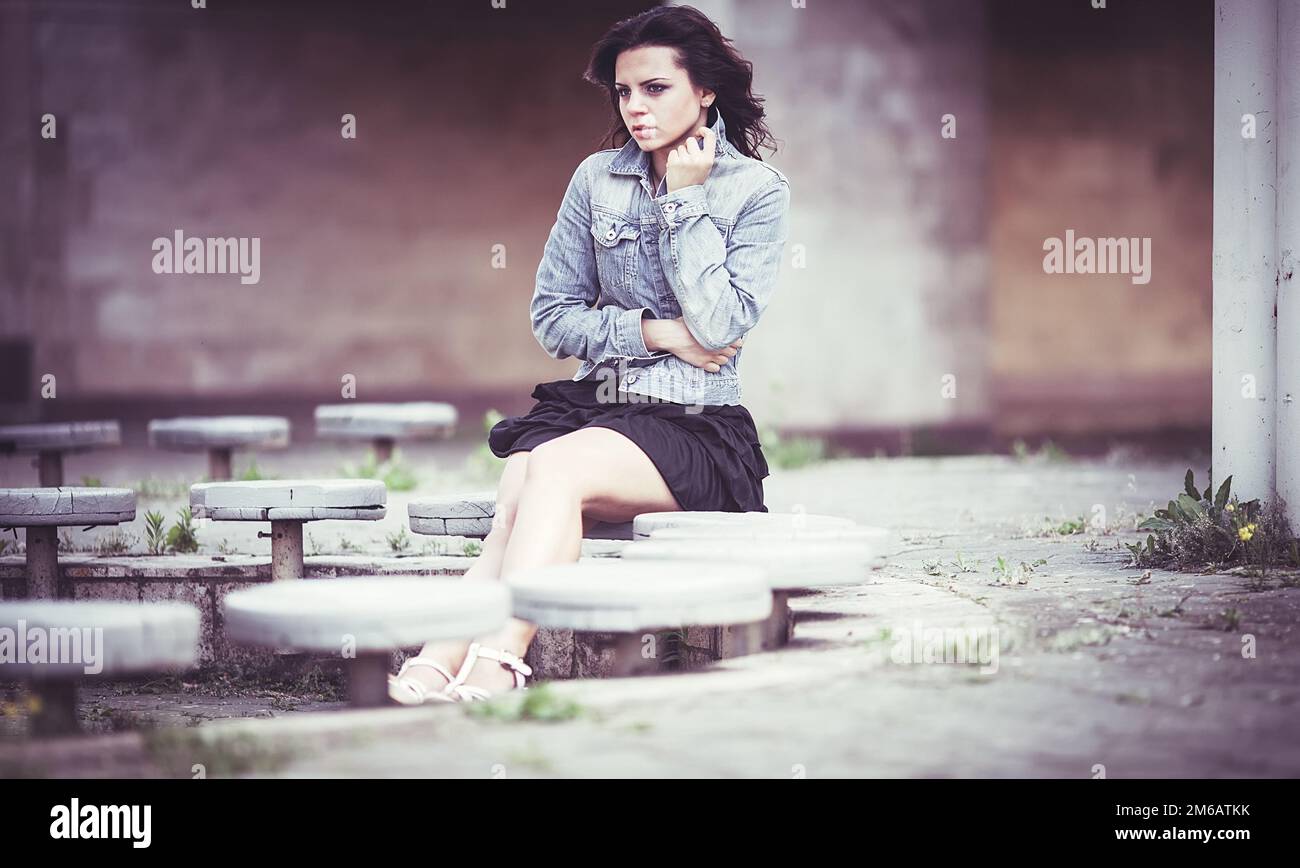 Girl on bench in denim jacket Stock Photo - Alamy