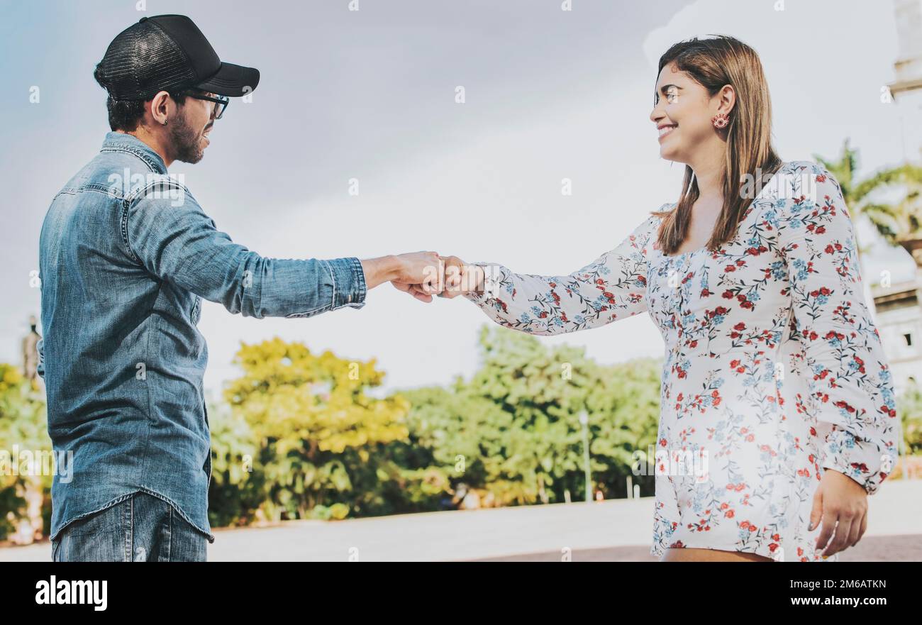A guy and girl shaking hands on the street. Two young smiling teenagers ...