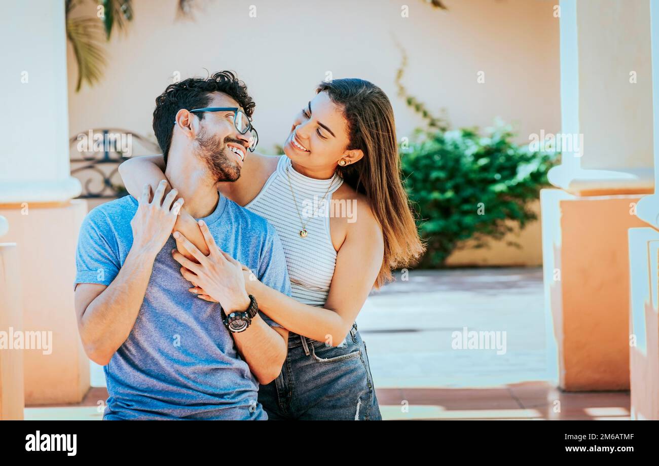 Girl hugging her boyfriend from behind. Smiling woman hugging her boyfriend from behind while he ...