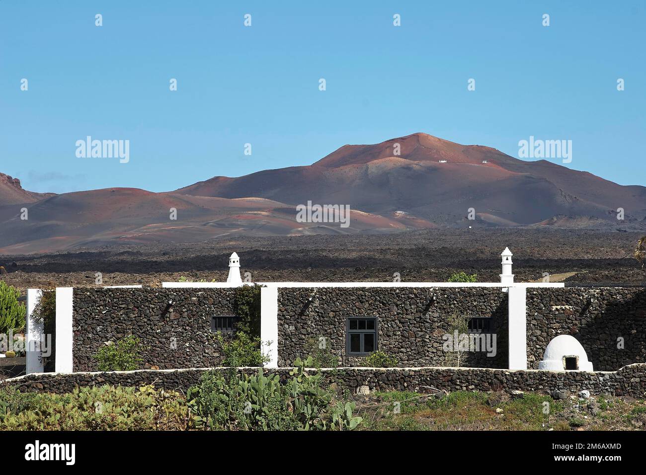 La Geria, black lava stone building, reddish brown lava mountains ...