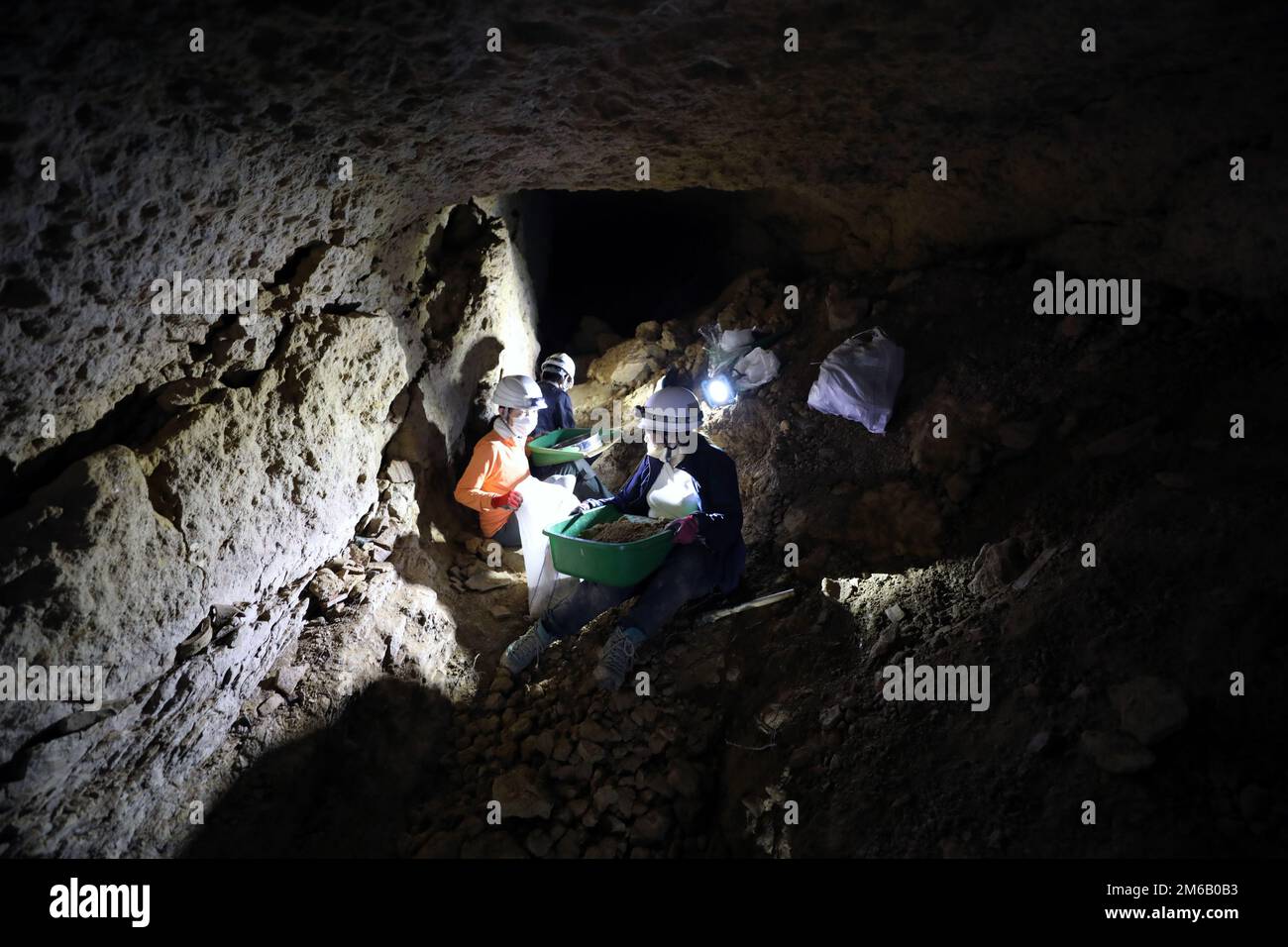 Japanese volunteers comb through the dirt and clay in a World War II ...