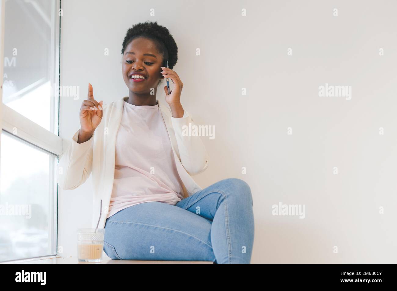 A charming young African woma smiling, answering her friend's phone ...