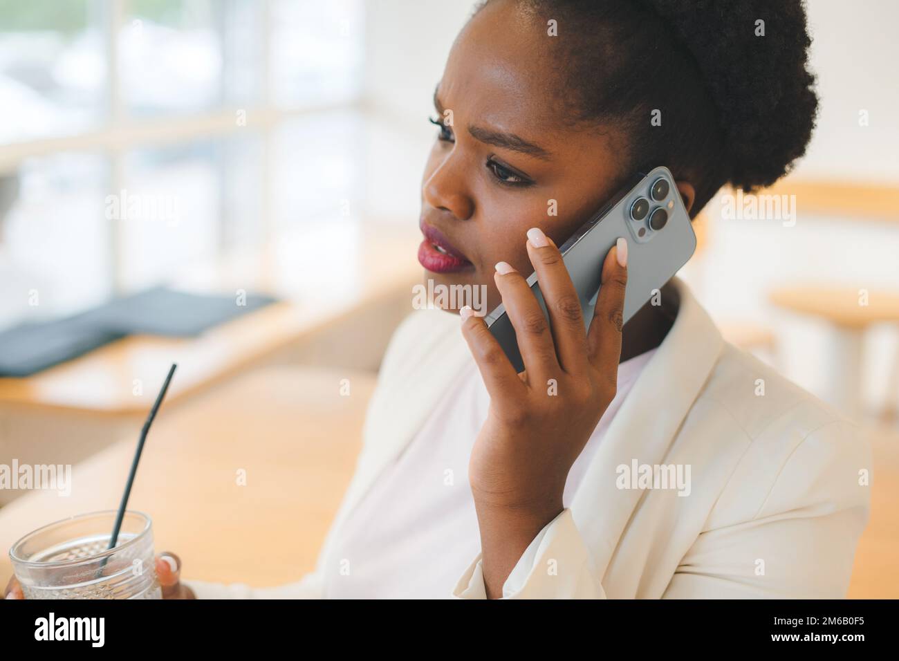African-american woman sitting at table of coffee shop, calling by ...