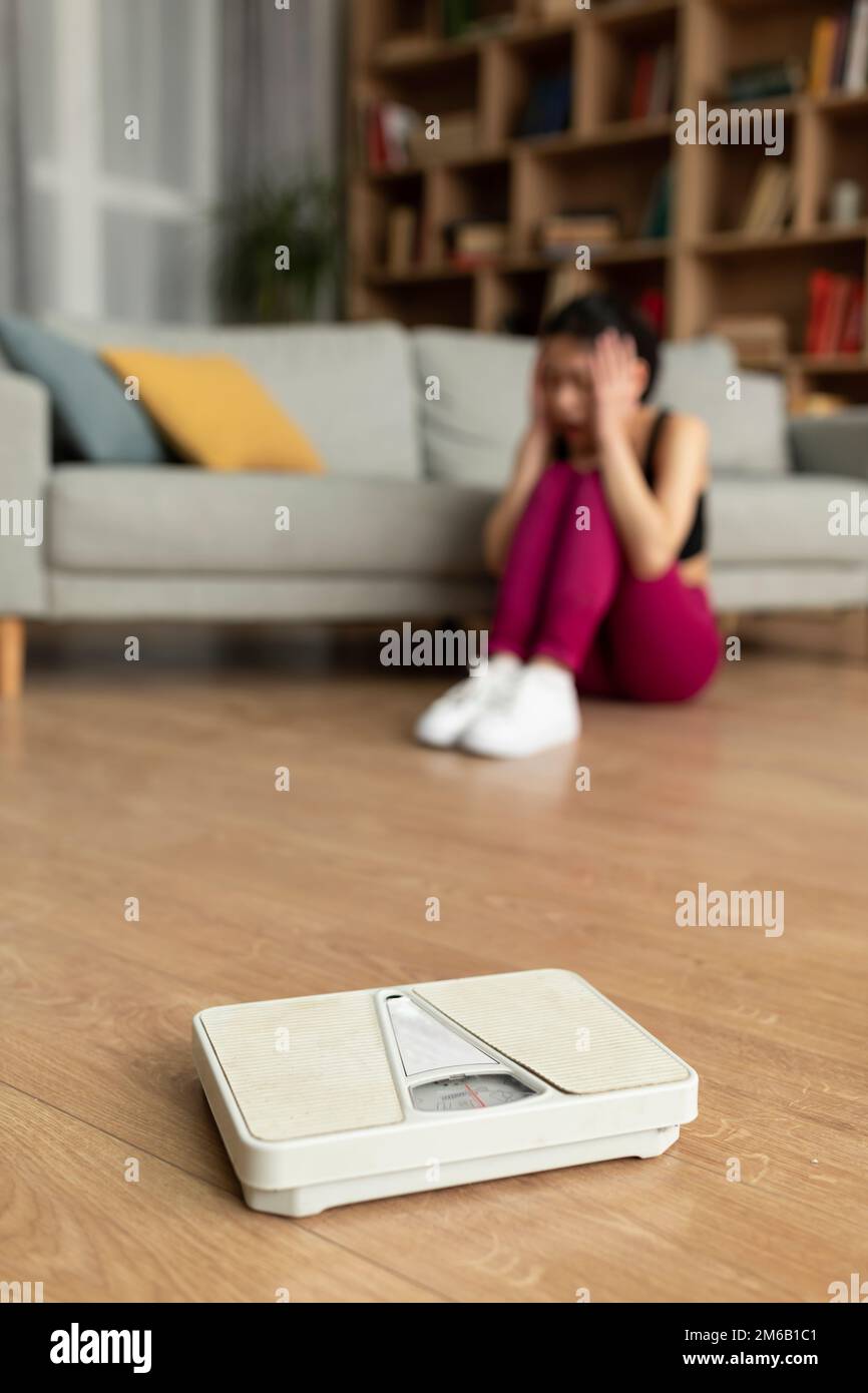 Weight-loss fail. Depressed korean lady crying, sitting near weight ...