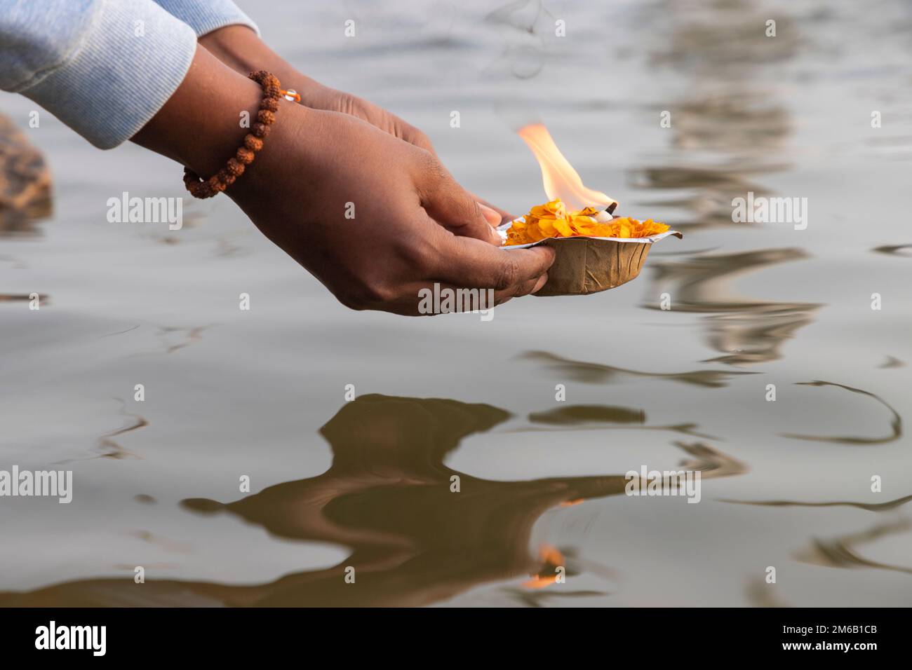 A devotee releasing the worship lamp diya as a ritual in the river ...
