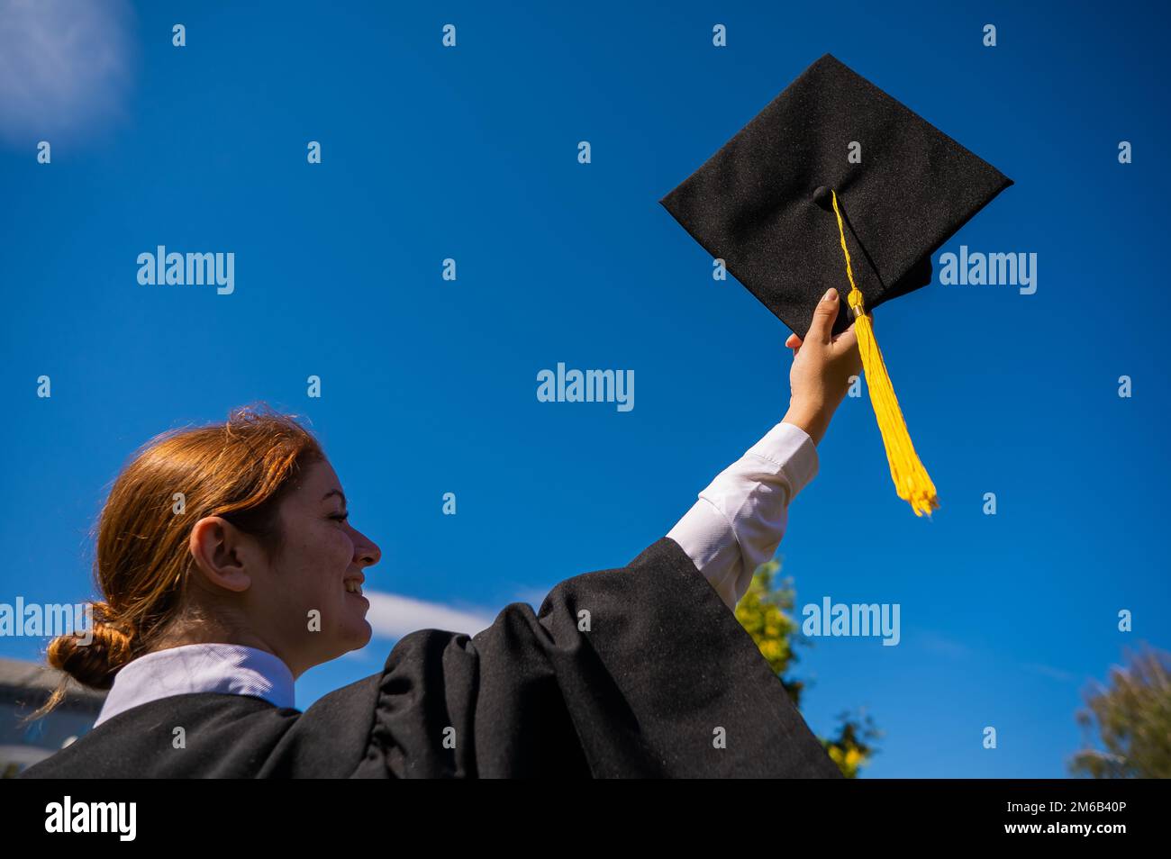 A woman throws her graduation cap against the blue sky Stock Photo - Alamy