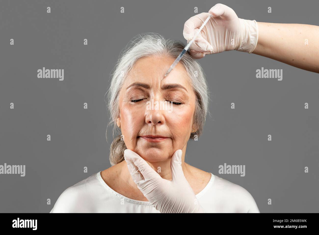 Serious old caucasian lady with closed eyes on beauty procedure ...