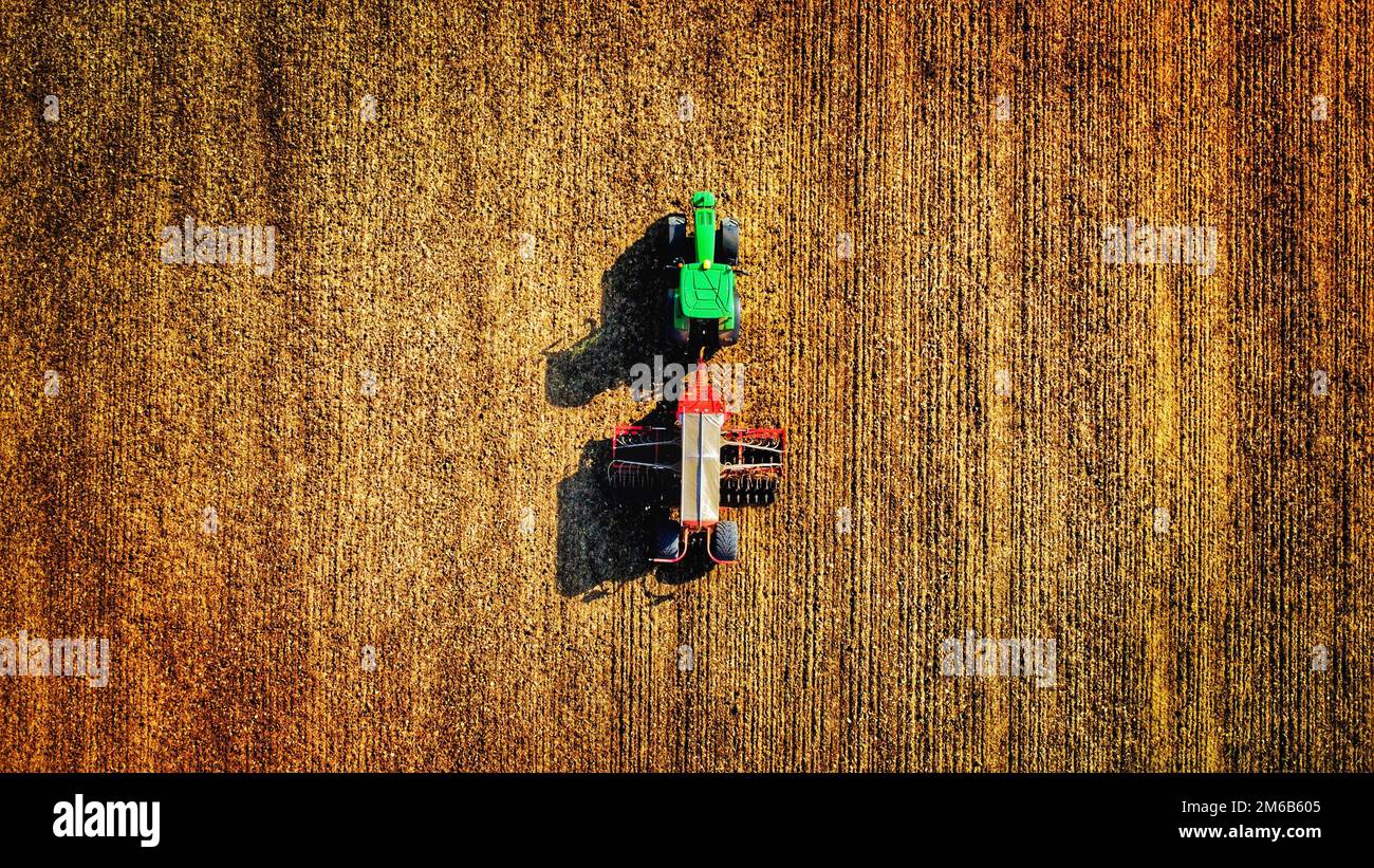 An aerial shot of a plough tractor at a newly toiled field Stock Photo ...