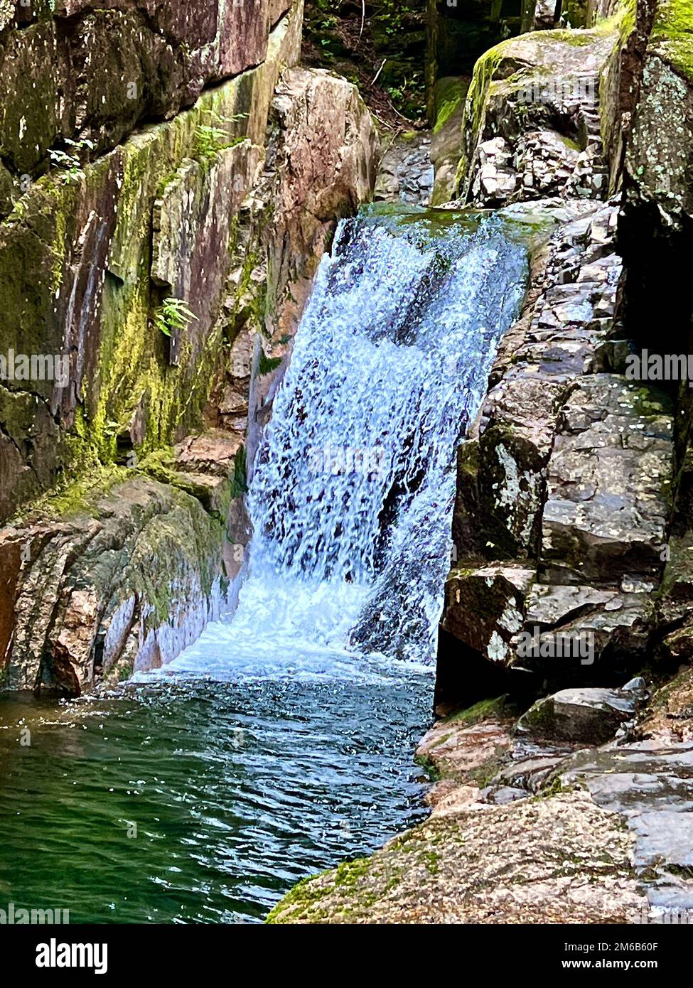 A vertical shot of a waterfall cascading between boulders at a mountain ...
