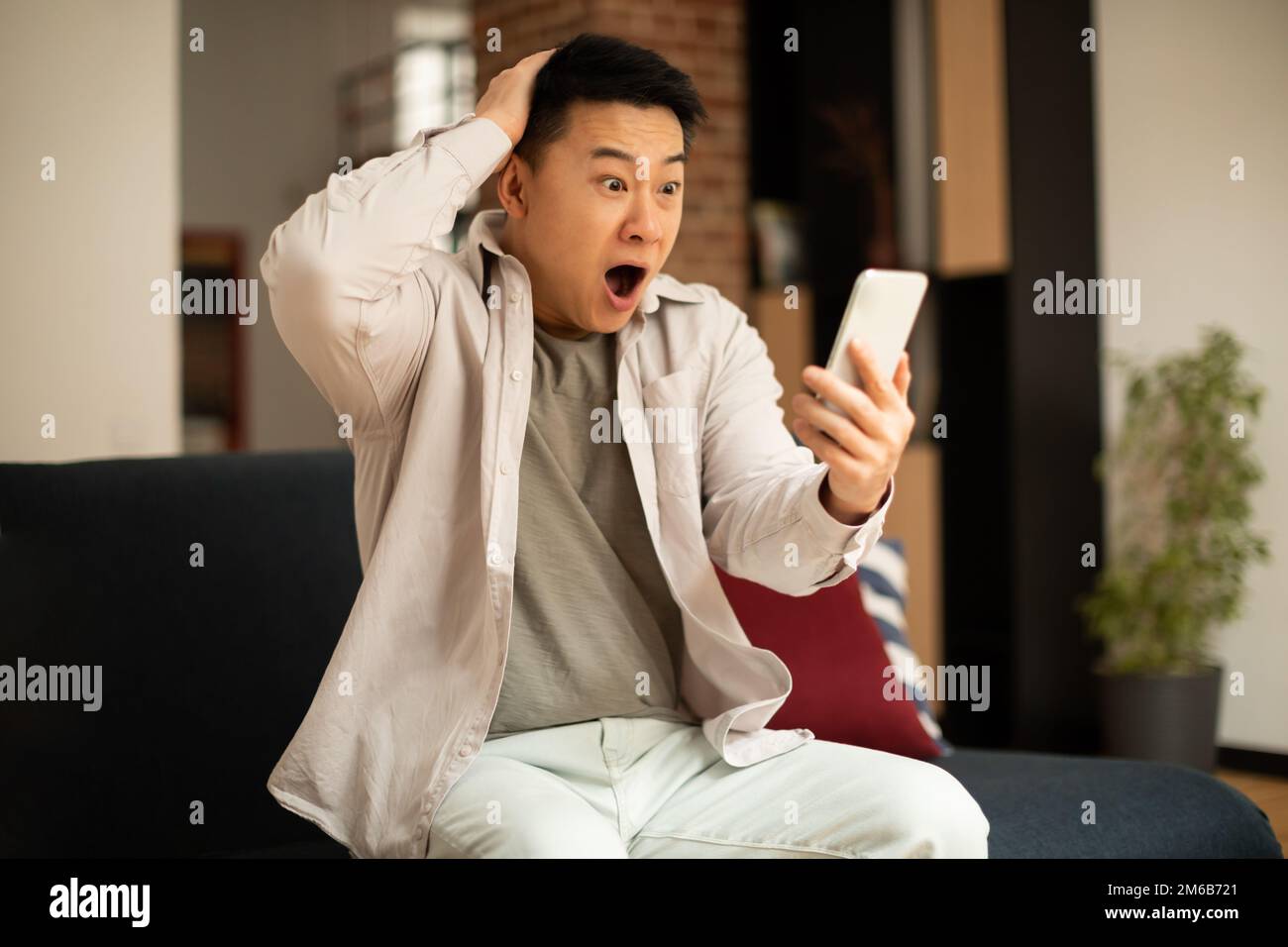 Oh no. Shocked mature asian man reading bad message on smartphone while ...